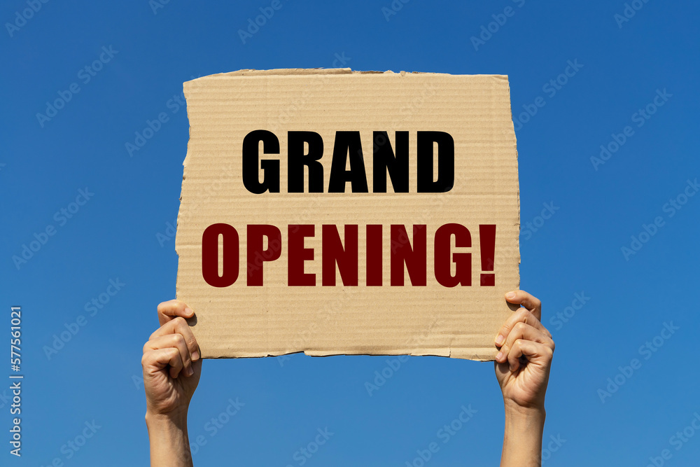 Grand opening message on box paper held by 2 hands with isolated blue ...