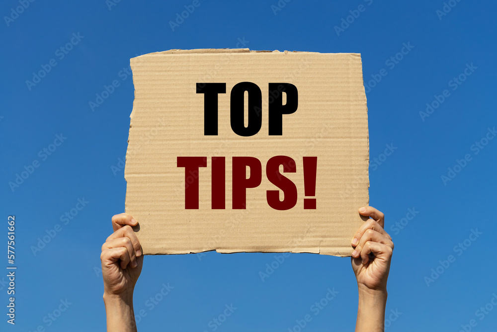 Foto de Top tips text on box paper held by 2 hands with isolated blue ...