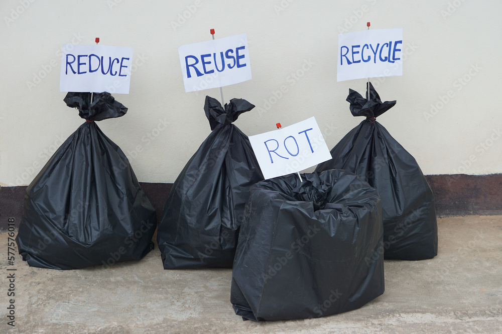 Foto de Back plastic bags that contain garbage inside.Paper signs with ...