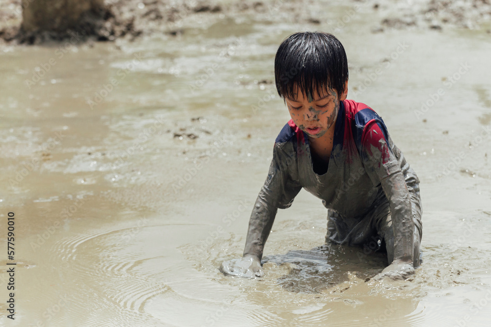 cute happy asian little boy enjoying to play in the mud at playground ...