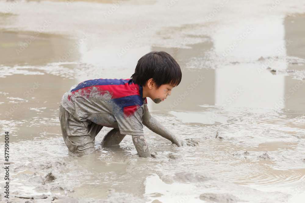 Foto Stock cute happy asian little boy enjoying to play in the mud at ...