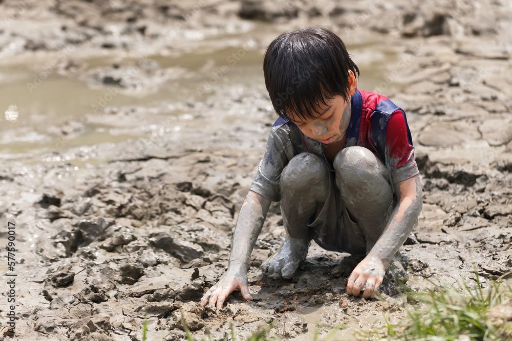 Foto de cute happy asian little boy enjoying to play in the mud at ...