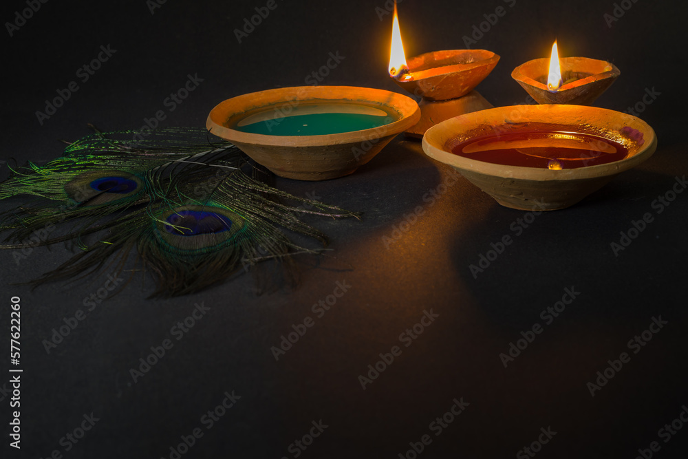 happy holi celebration with colors, clay lamp and peacock feather ...