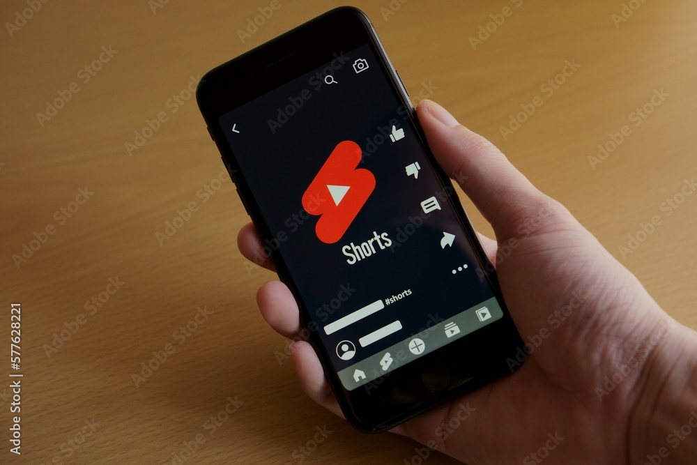 The screen of "Youtube Shorts" is displayed on the smartphone in hand. "Youtube Shorts" are ...