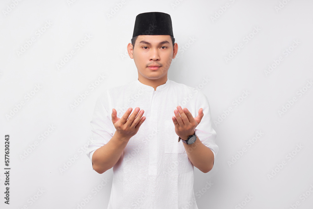 Handsome young Asian Muslim man in Arabic costume standing with raising ...