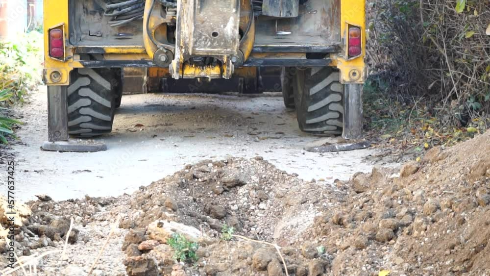Excavator digs a trench to lay pipes. Close up of an excavator digging ...