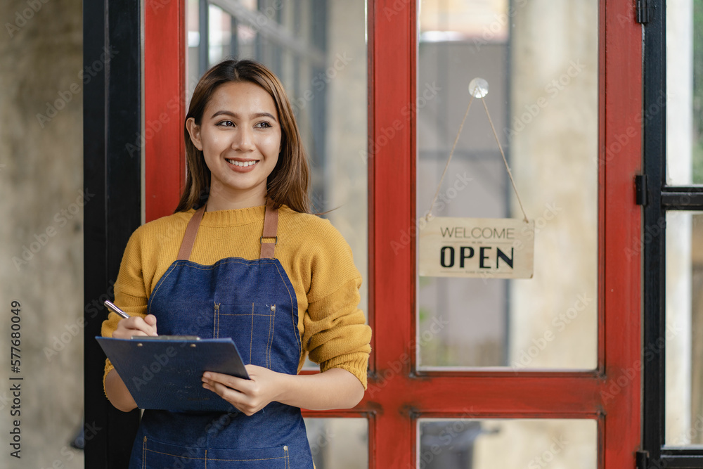 Beautiful Asian barista in apron holding tablet and standing in front ...