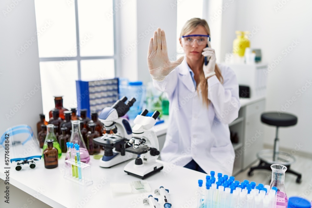 Beautiful woman working at scientist laboratory speaking on the phone ...