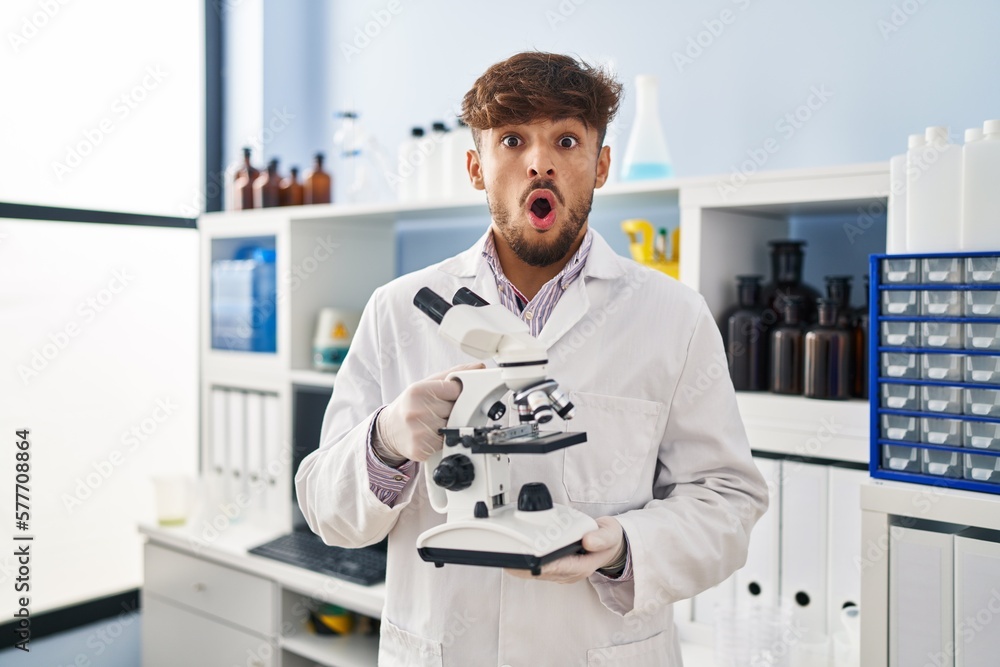 Arab man with beard working at scientist laboratory holding microscope ...