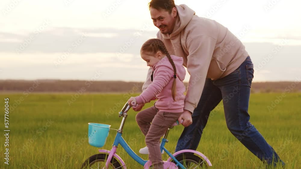 father rides child two-wheeled bicycle sunset. happy family. happy ...