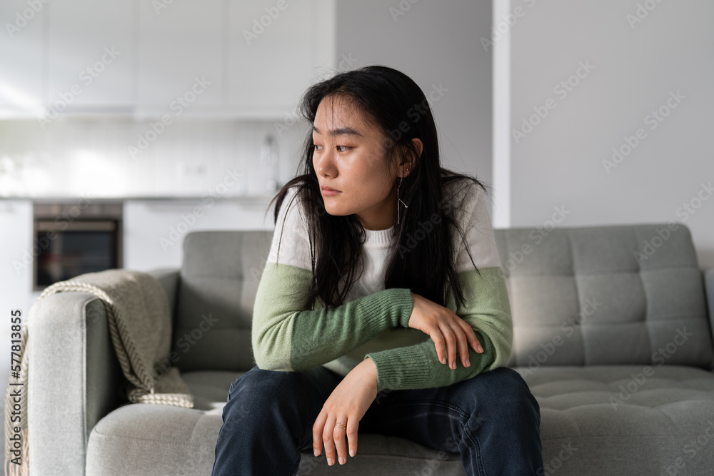 Sad lonely young Asian woman having depression symptoms, sitting on ...