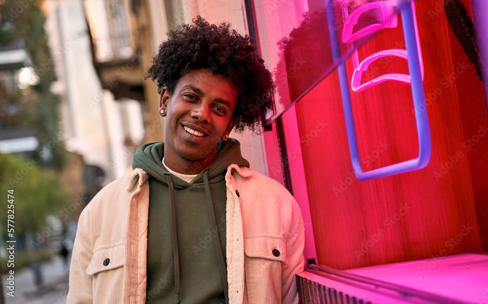 Smiling cool young African American hipster guy standing at city street ...