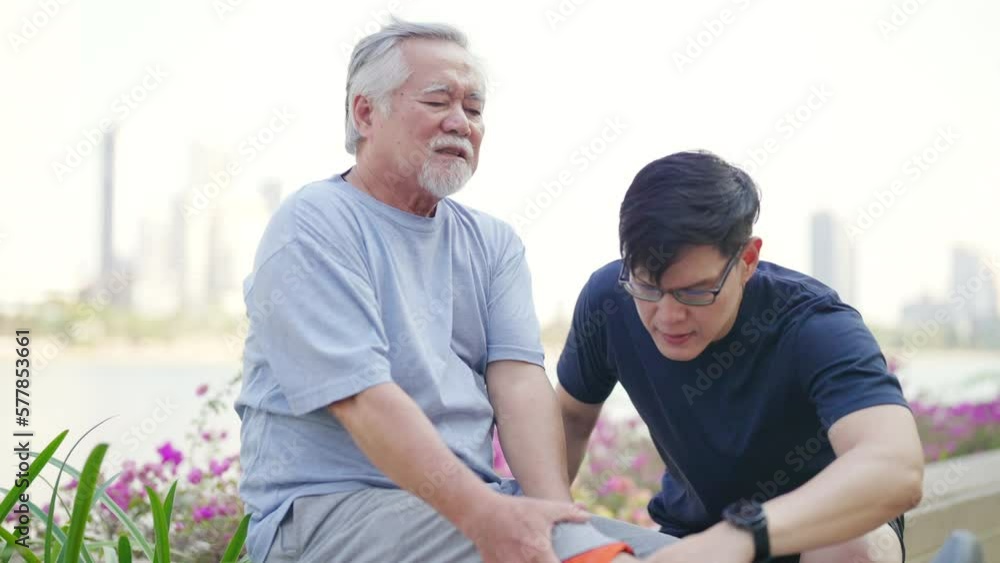 Elderly man suffering knee pain during jogging exercise with his son at ...