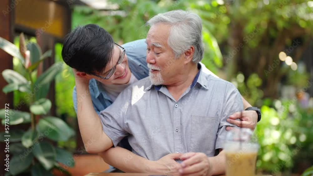 Asian man surprise hugging elderly father from back at outdoor garden ...