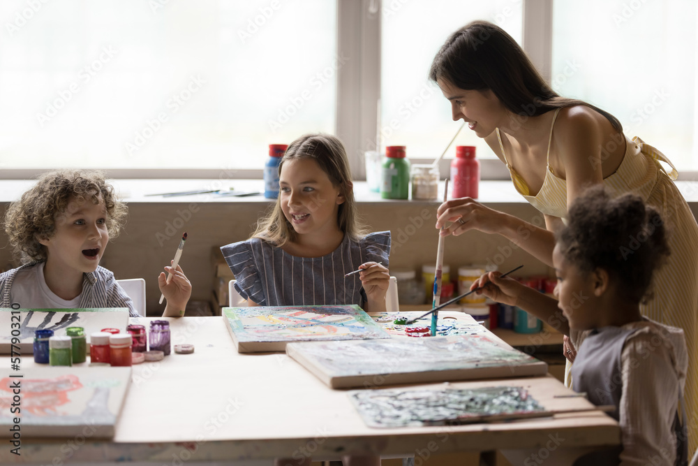 Foto de Happy pretty art school teacher giving lesson to pupil kids ...