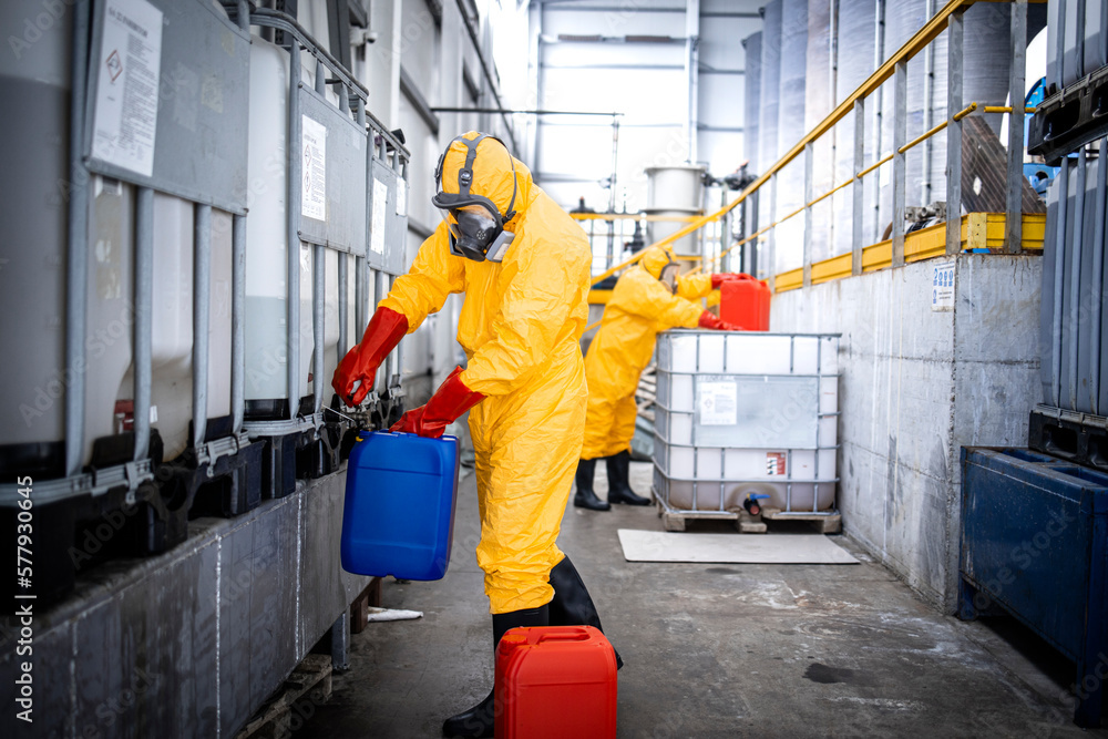 Factory workers in metal industry filling canisters with acids and ...