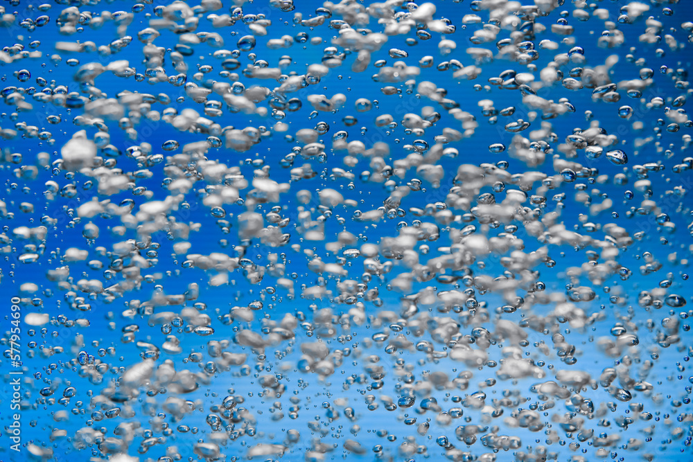 A stream of shiny air bubbles illuminated by light and shining on a ...