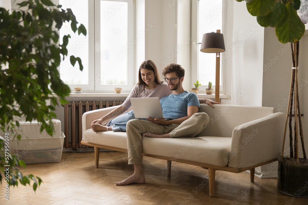 Foto Stock Cheerful millennial young husband and wife using laptop for ...