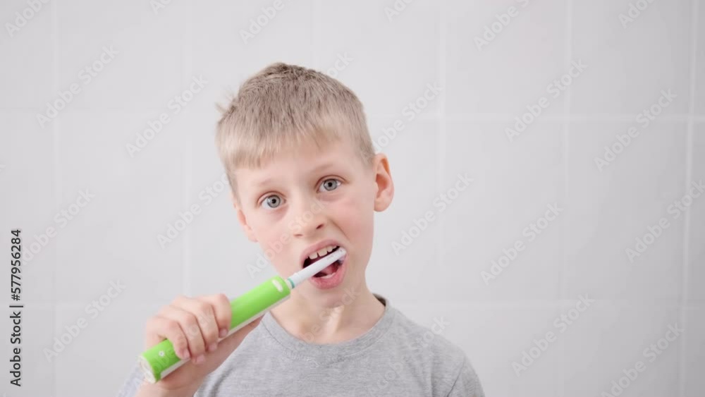 cute boy brushing teeth with an electric brush and then funny shows ...