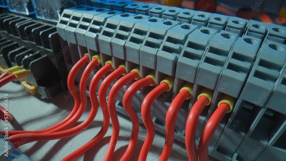 Gray plastic electrical panel with many red wires, yellow bushing ...
