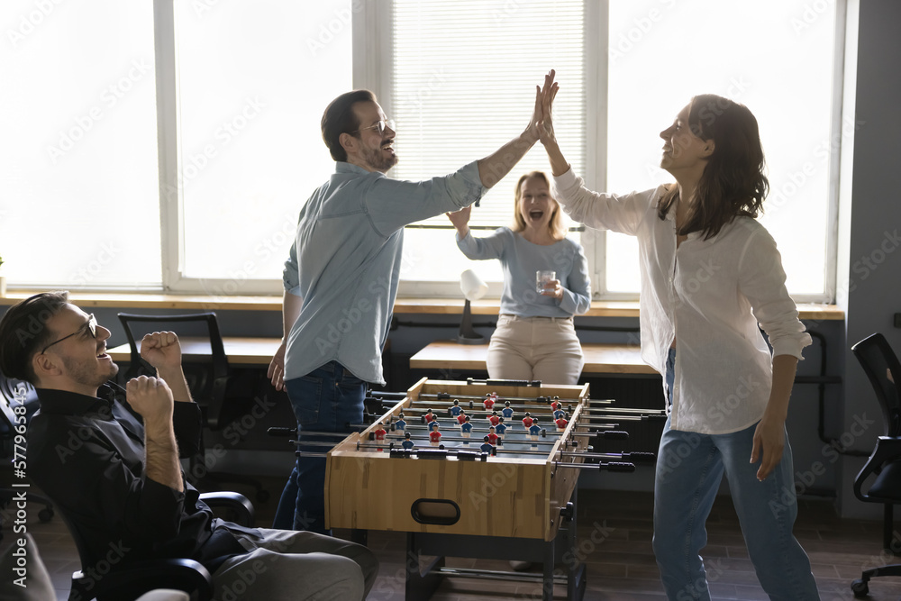 Foto de Excited happy business friends playing tabletop football ...