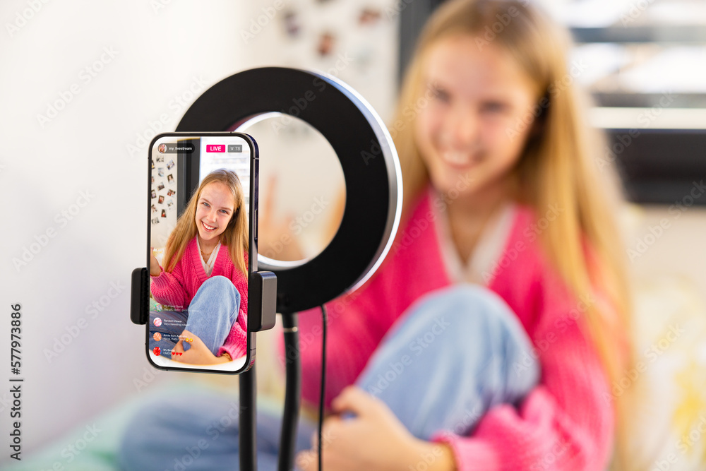 Teenage girl filming herself with mobile phone at home and live ...
