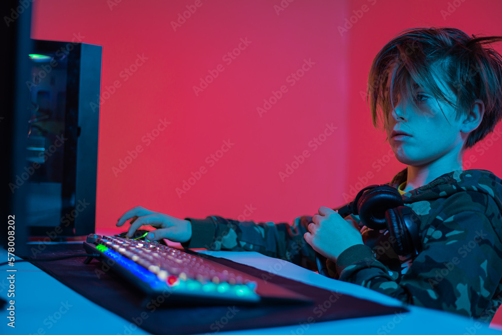 Portrait of gamer boy playing video games on computer in dark room ...