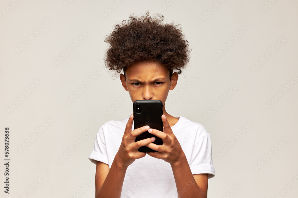 Frustrated african kid boy standing against gray studio background with ...