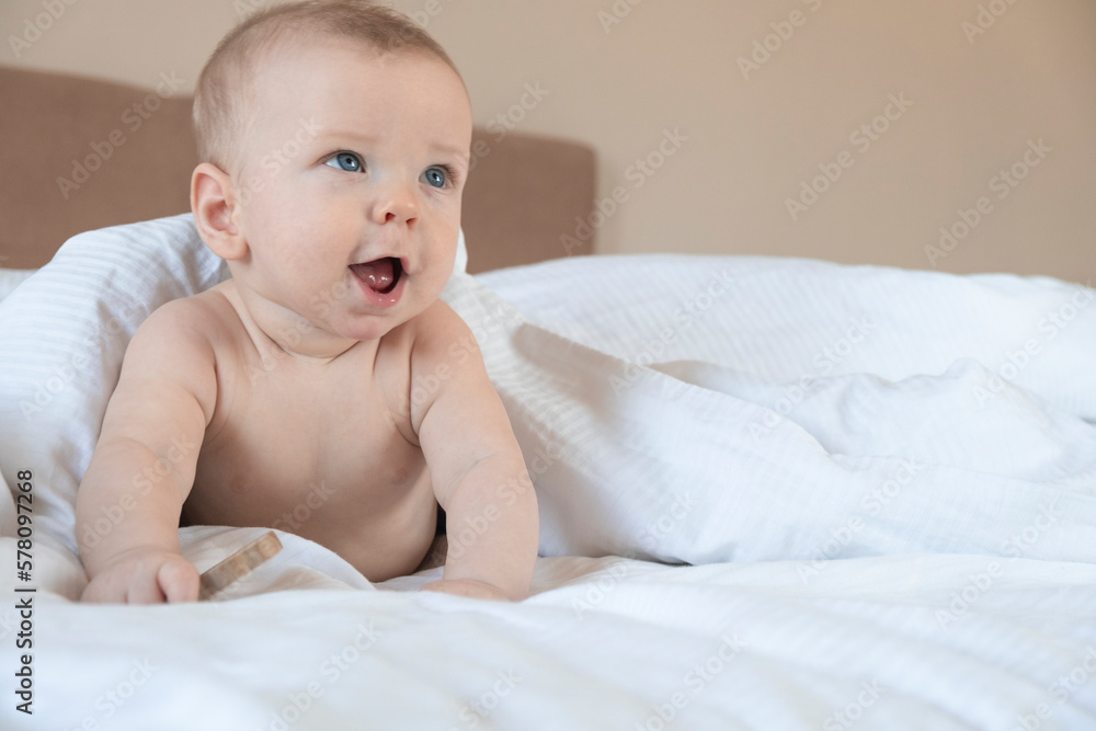 Cute little baby laying on tummy with straight hands in bed with white ...