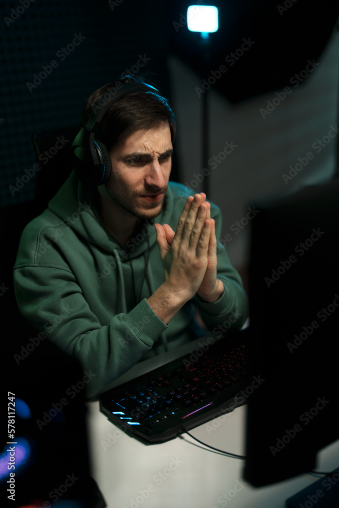 High angle of young worried male cybersport gamer sitting at table with ...