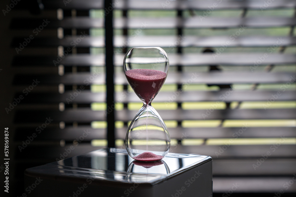 Sand running or flowing down of an hourglass measuring the passing of ...