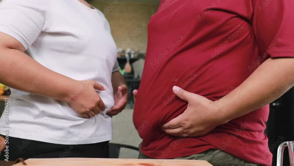 Obese man and woman couple shake their belly with their hands on their ...