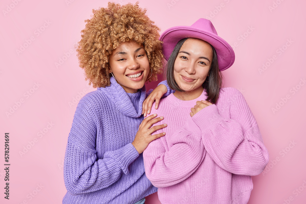Portrait of happy charming female models wear warm knitted jumpers and ...