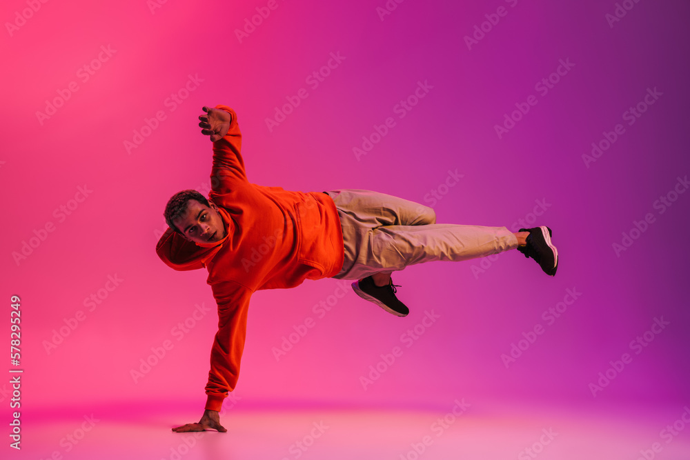 African man standing on one hand while dancing isolated over pink ...