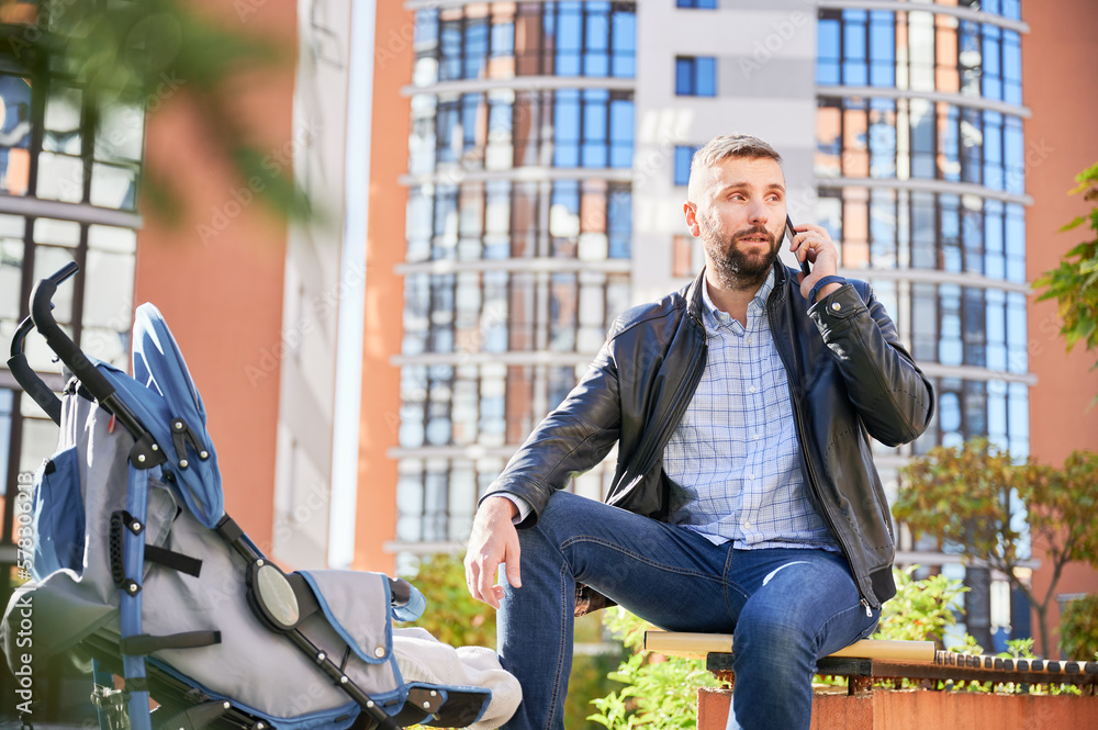 Father making business call, while spending time with baby outdoors ...