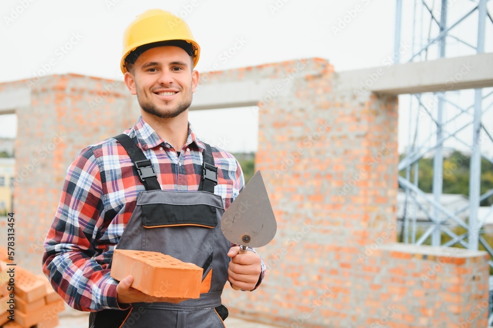 Installing brick wall. Construction worker in uniform and safety ...