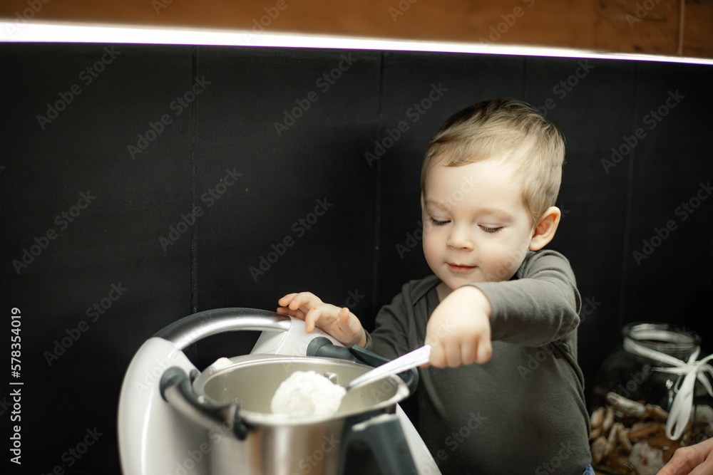 Little boy child help and learn cook in kitchen. Putting flour and ...