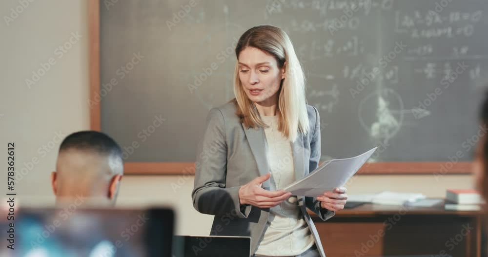 Caucasian female teacher talking with students, explaining material and ...
