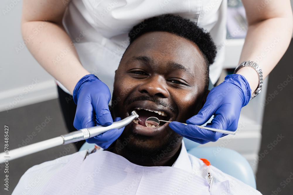 Stockfoto Dentist is drilling teeth and removing caries of african man ...