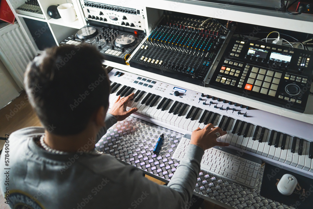 high-angle back view of a young man playing the electronic piano in his ...