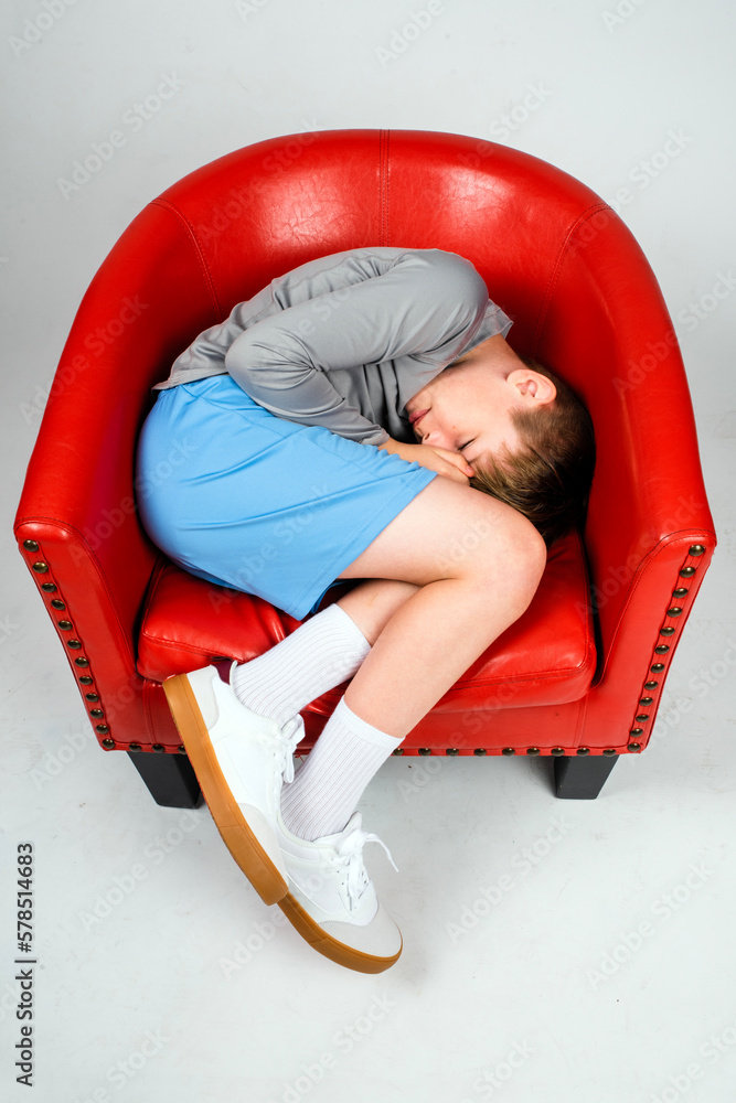 Male preteen child curled up sleeping on a red chair Stock Photo ...