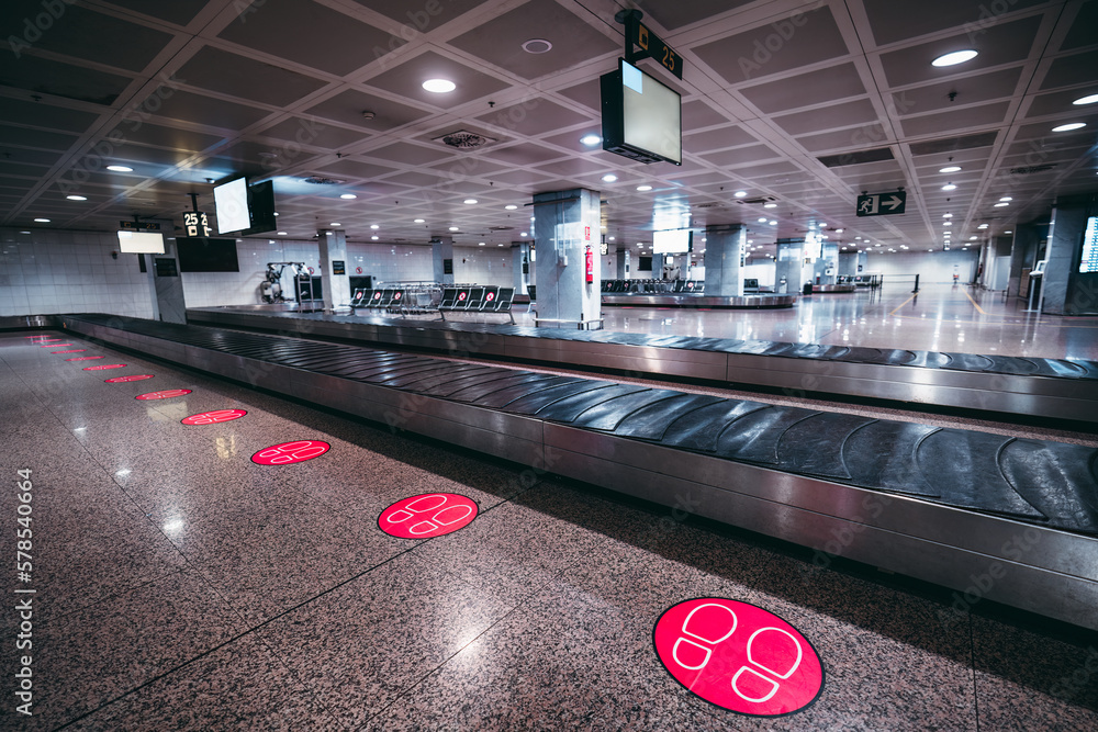 A clear baggage claim area in the Lisbon airport, low-key. On the floor ...