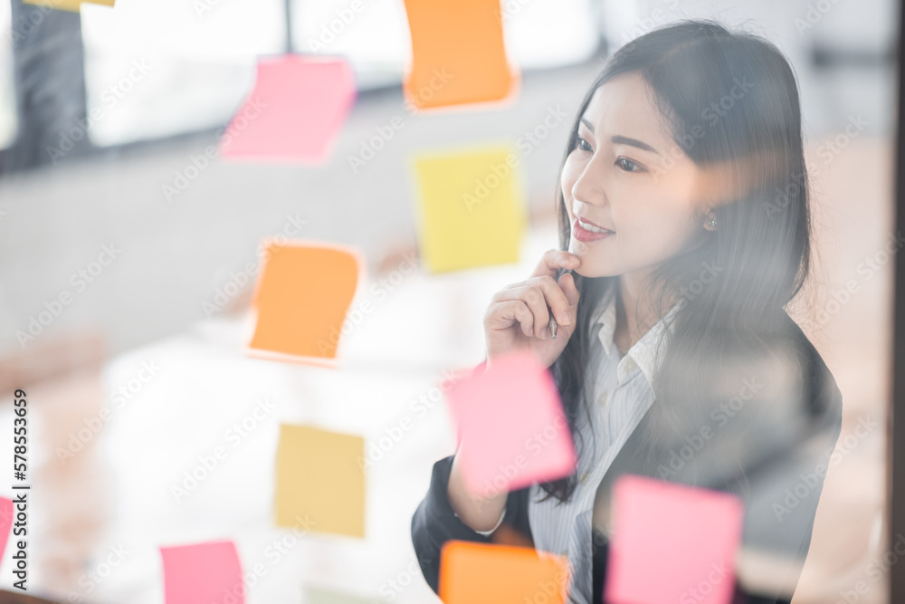 Young Serious Asian Creative team use post it notes to share idea ...