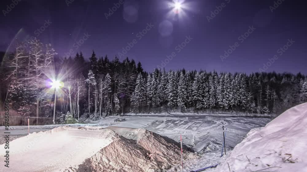Making a ski and snowboarding ramp jump at nighttime in the moonlight ...