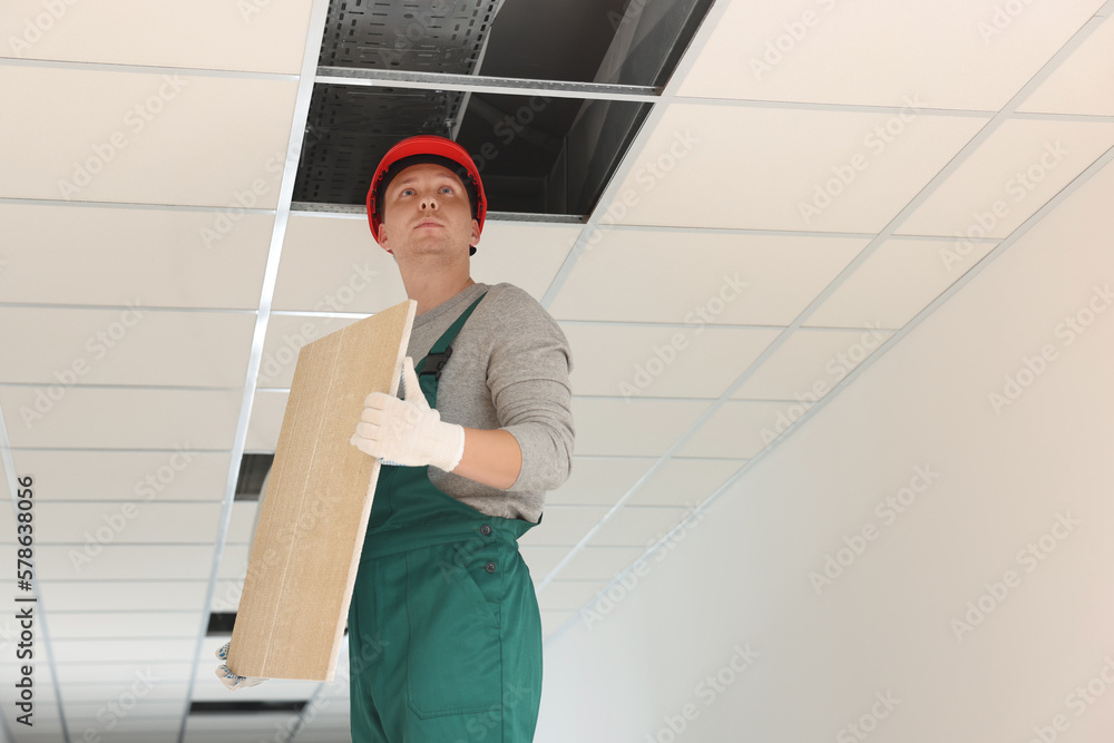 Suspended ceiling installation. Builder working with PVC tile Stock ...