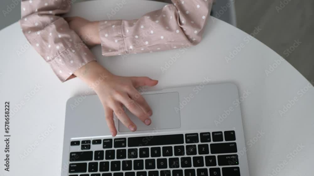 Top view child hands using the touchpad on laptop to study at home ...