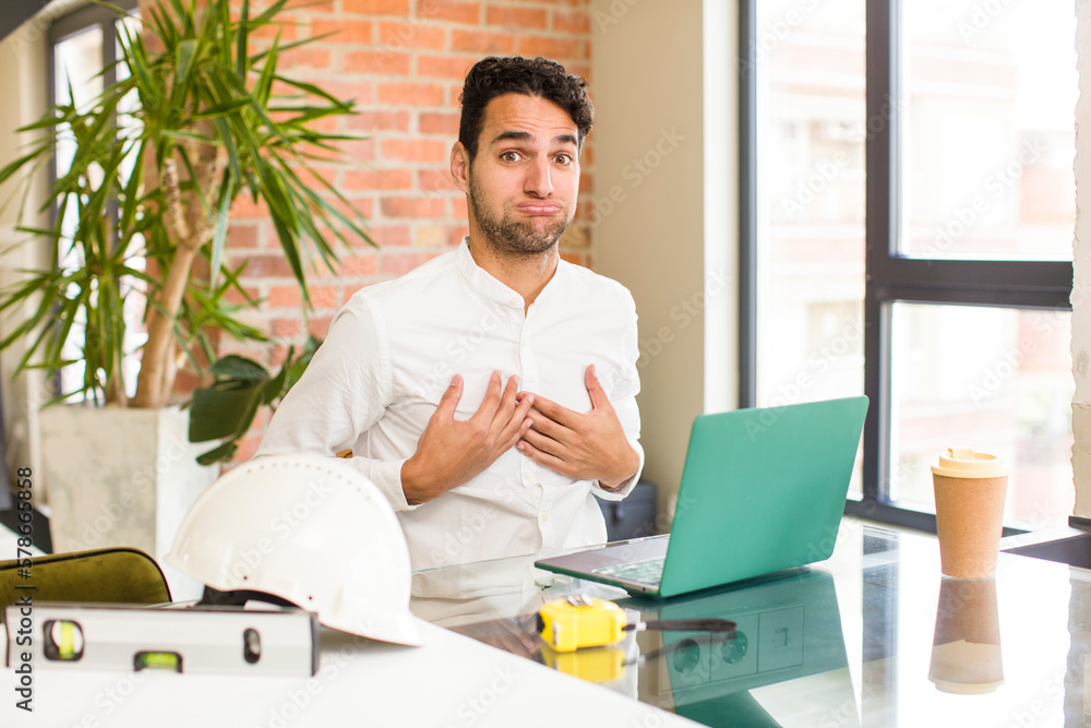 young hispanic man with a goofy, crazy, surprised expression, puffing ...