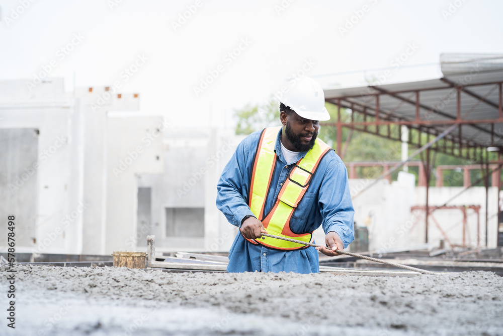 Construction worker uses long steel trowel spreading wet concrete ...