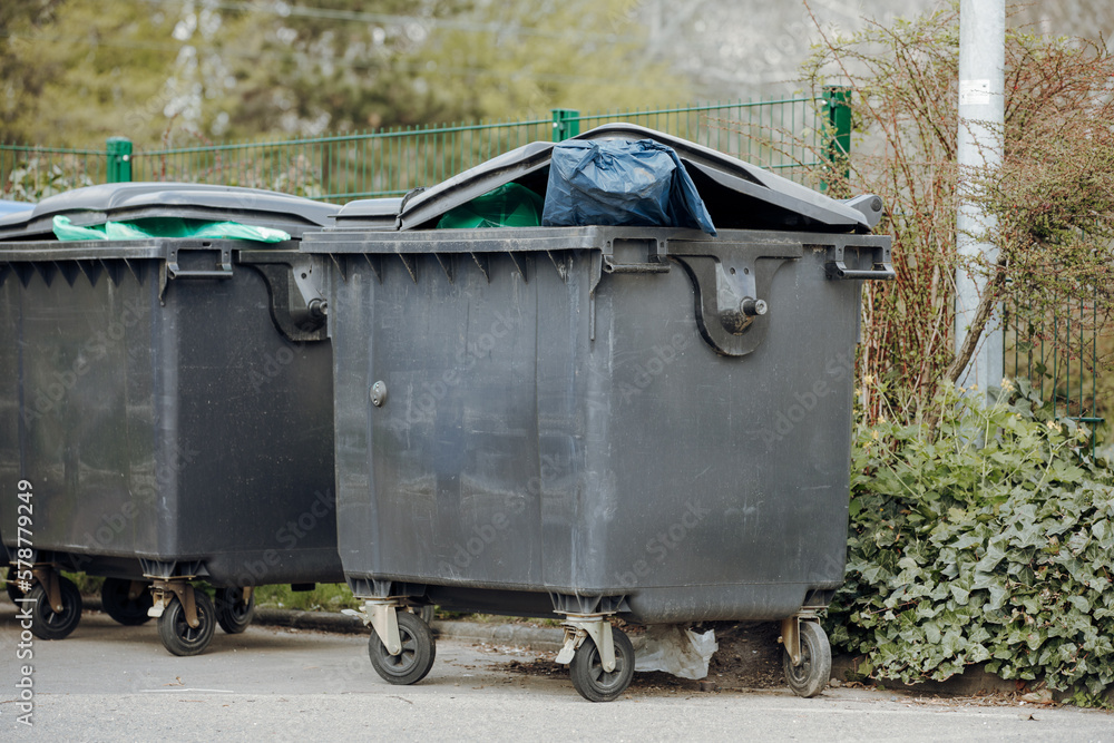 black trash container for waste, overload with garbage bags and open ...