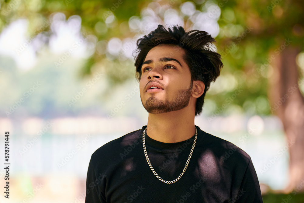 Attractive young indian man portrait in black t shirt and silver neck ...